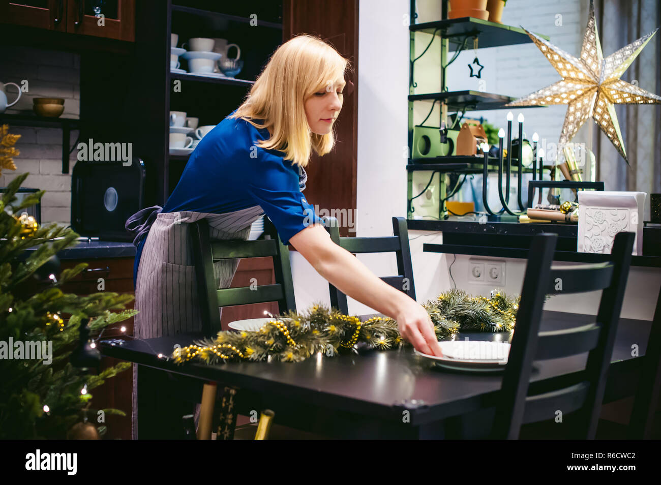 woman housewife setting the table. young blonde in a dress and apron ...