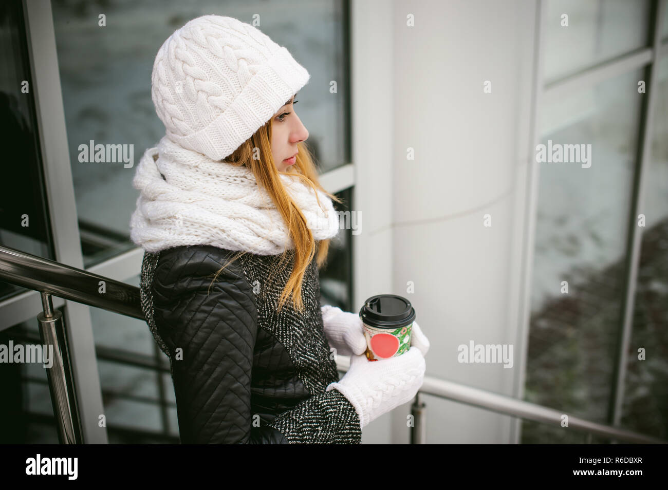 woman in white scarf and hat drinks coffee. cute young blond woman ...