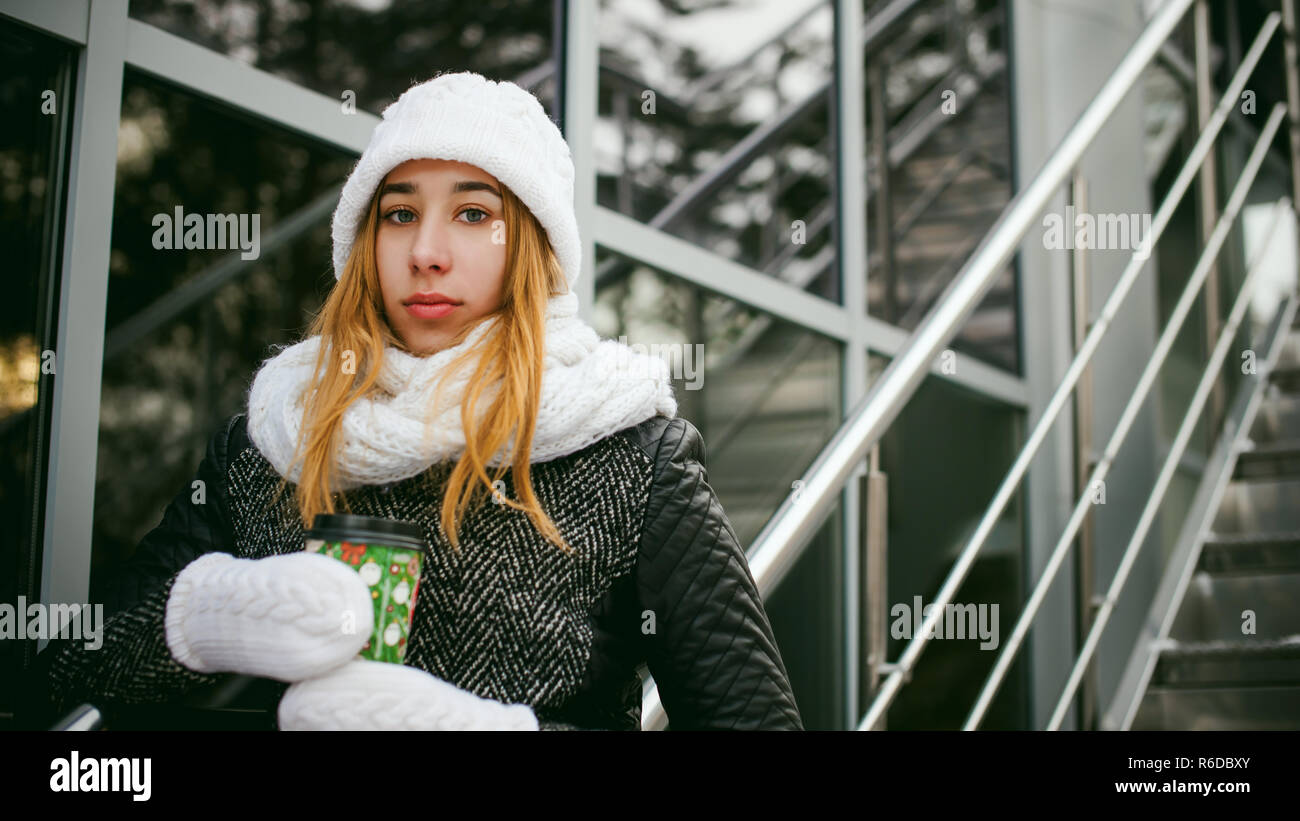 woman in white scarf and hat drinks coffee. cute young blond woman ...