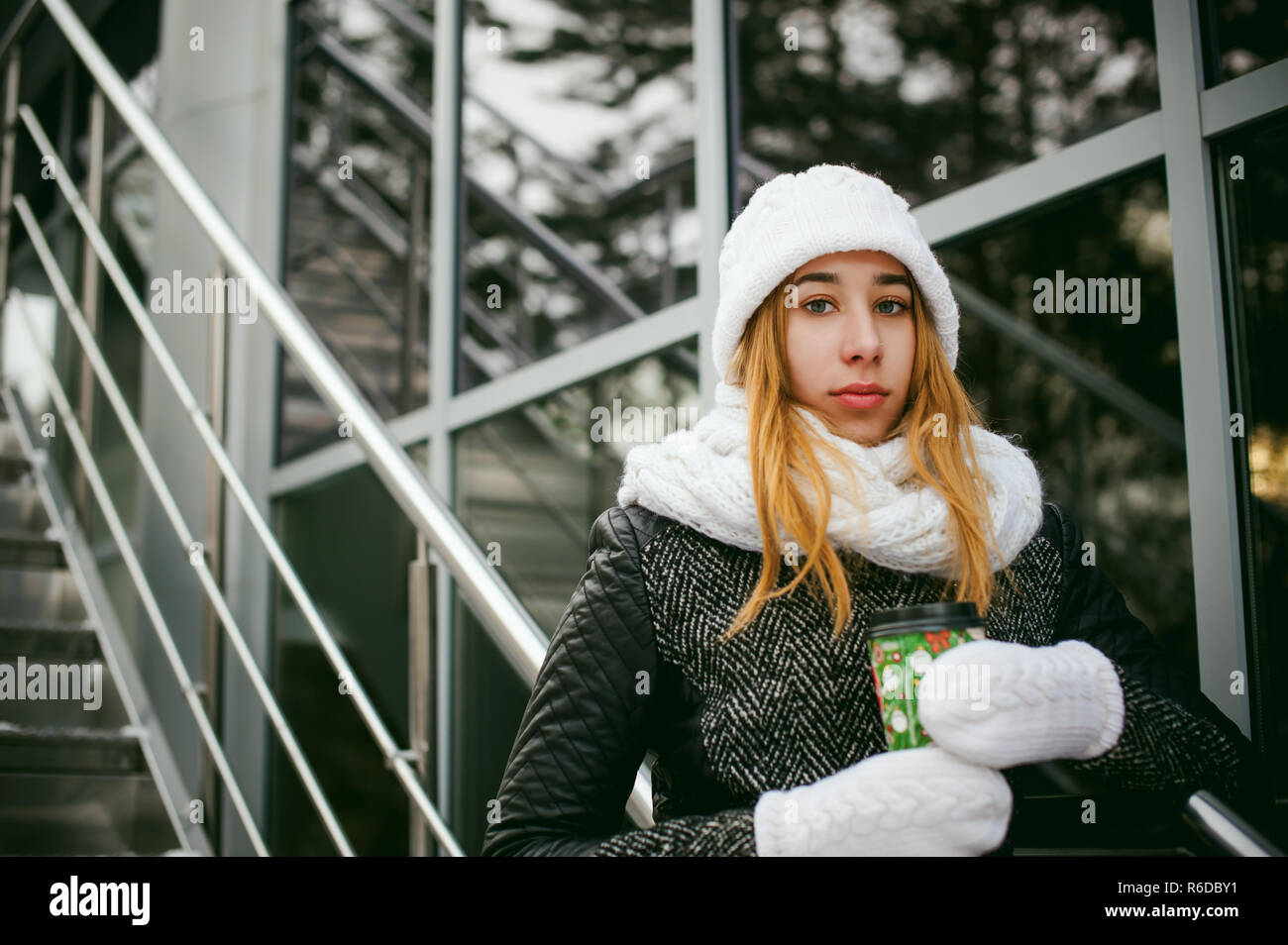 woman in white scarf and hat drinks coffee. cute young blond woman ...