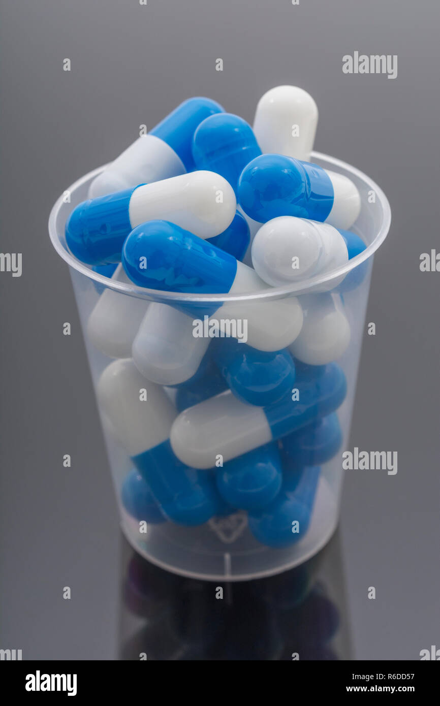 Big pharma medication concept. Blue and white capsules pills in plastic ...