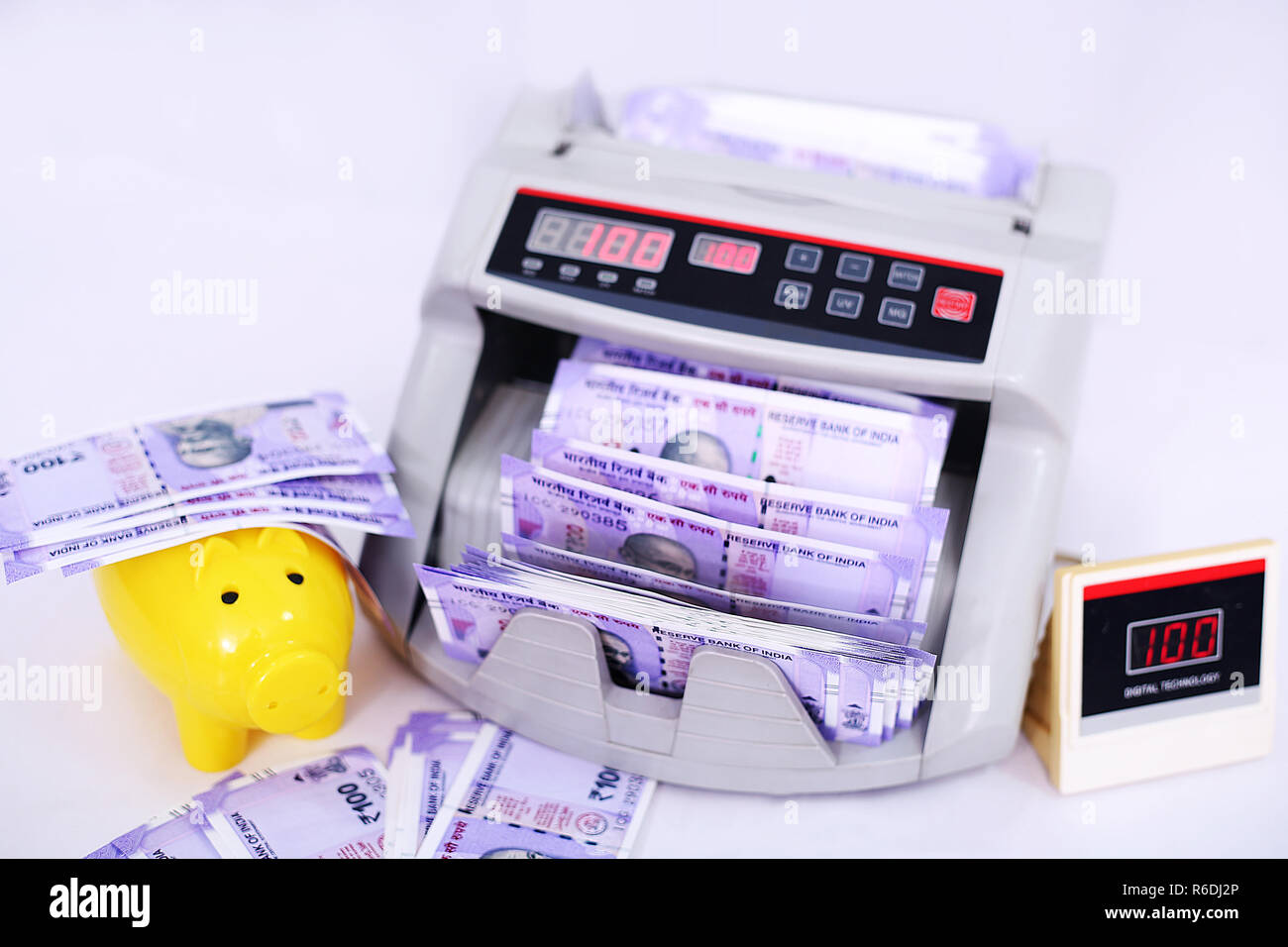 Money counting machine with new 100 rupees notes and piggy bank ...
