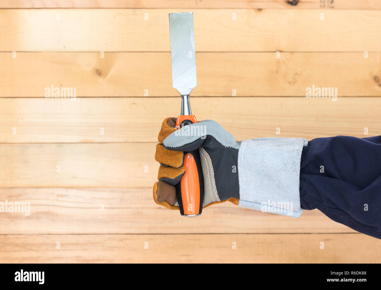 Hand in glove holding chisel Stock Photo - Alamy