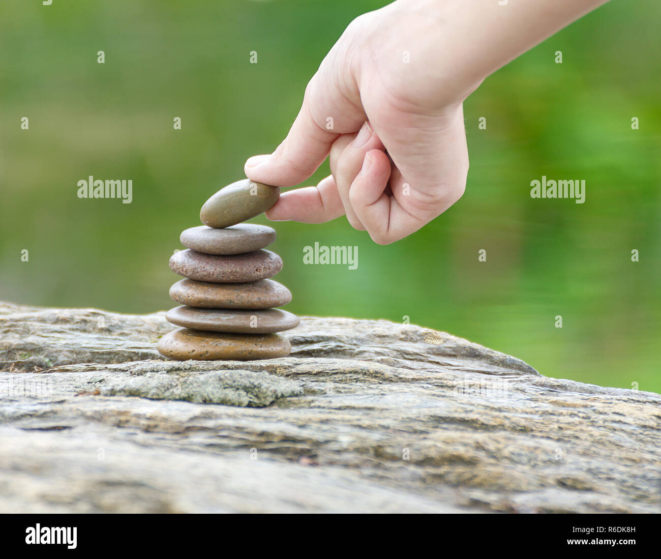 Hand put stone building a pile of zen stones Stock Photo - Alamy