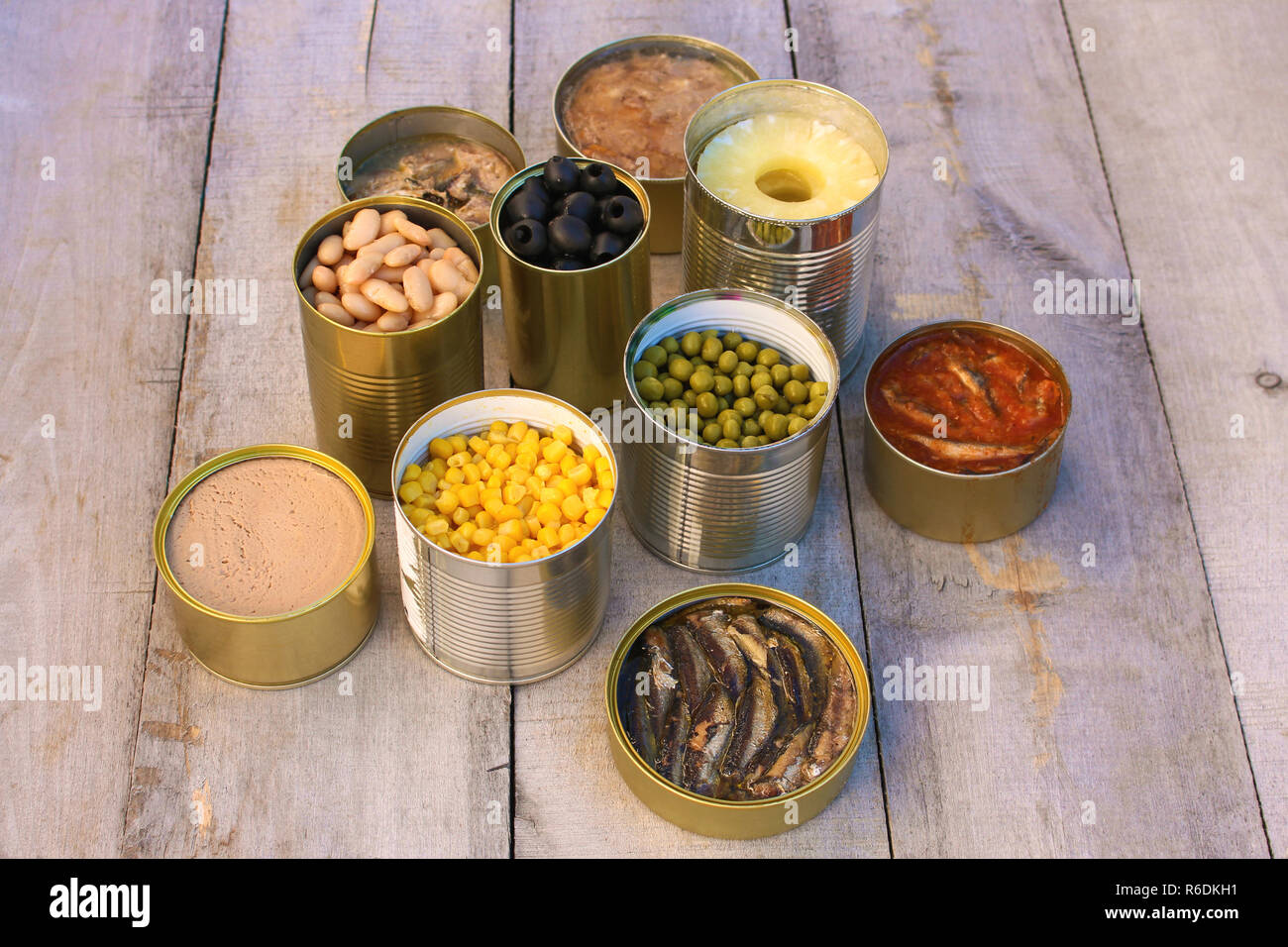 Different open canned food on old wooden background Stock Photo - Alamy