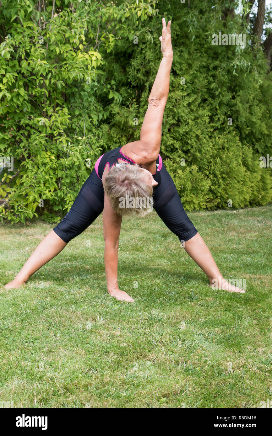 Senior blond woman in forward bend pose Stock Photo - Alamy