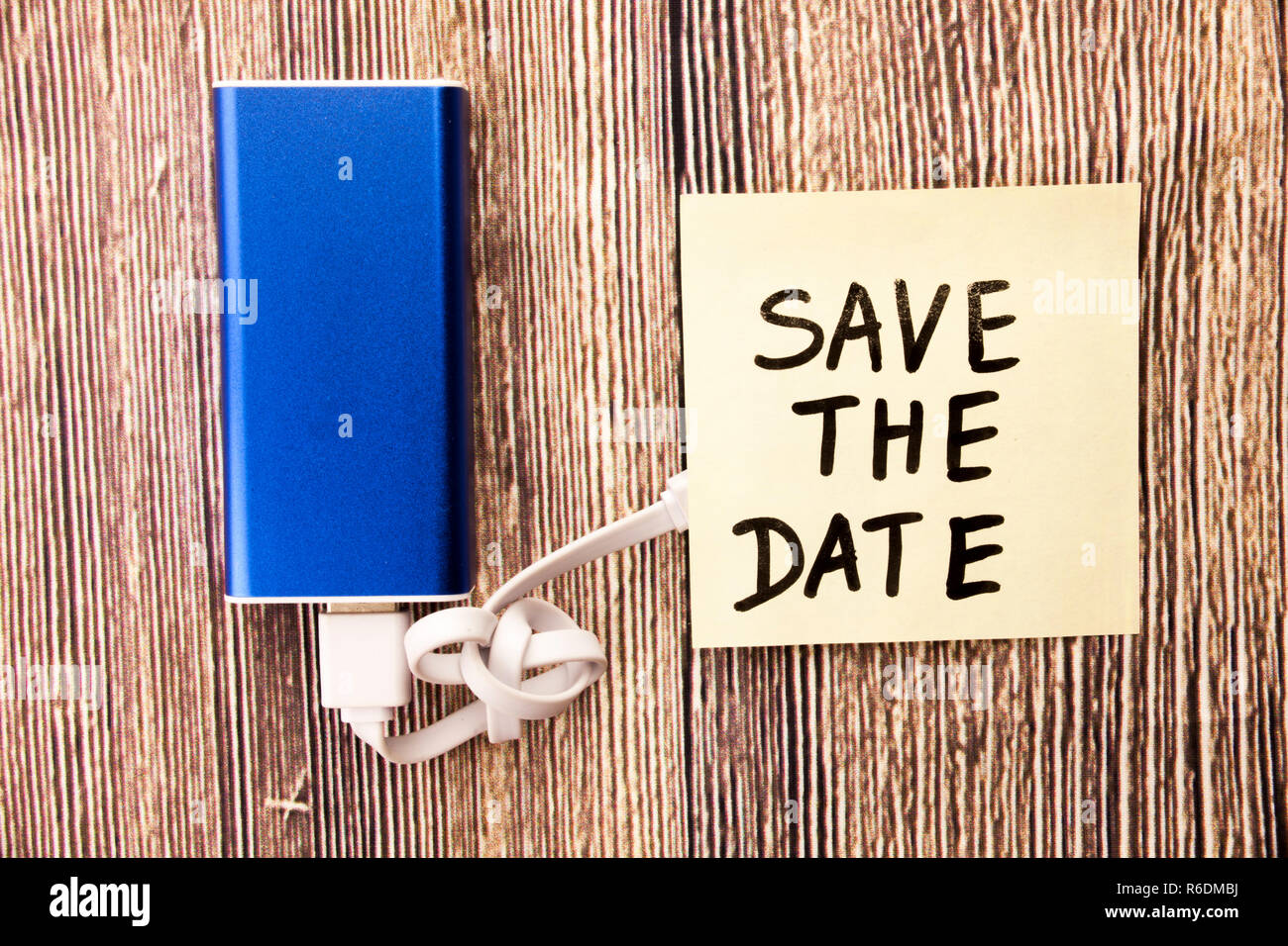 Save the Date sticky note paper charging with energy bank. Depth of ...