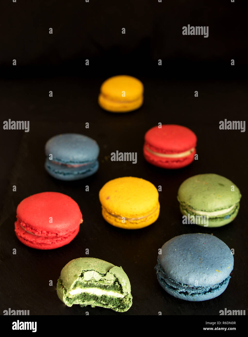 different colored and filled macaroons with a bitten piece Stock Photo ...