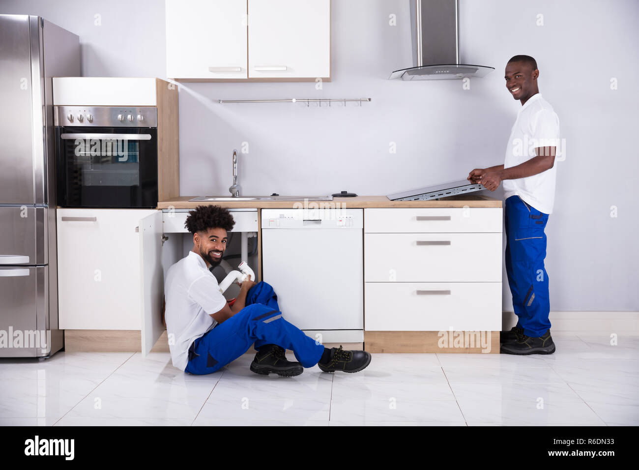 Two Young Service Men Fixing The Equipment In The Kitchen Stock Photo ...