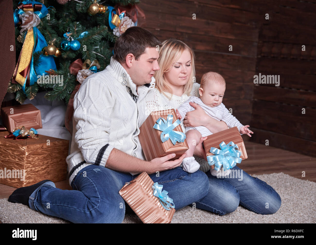 happy family with gift boxes sitting near Christmas tree on Christmas ...