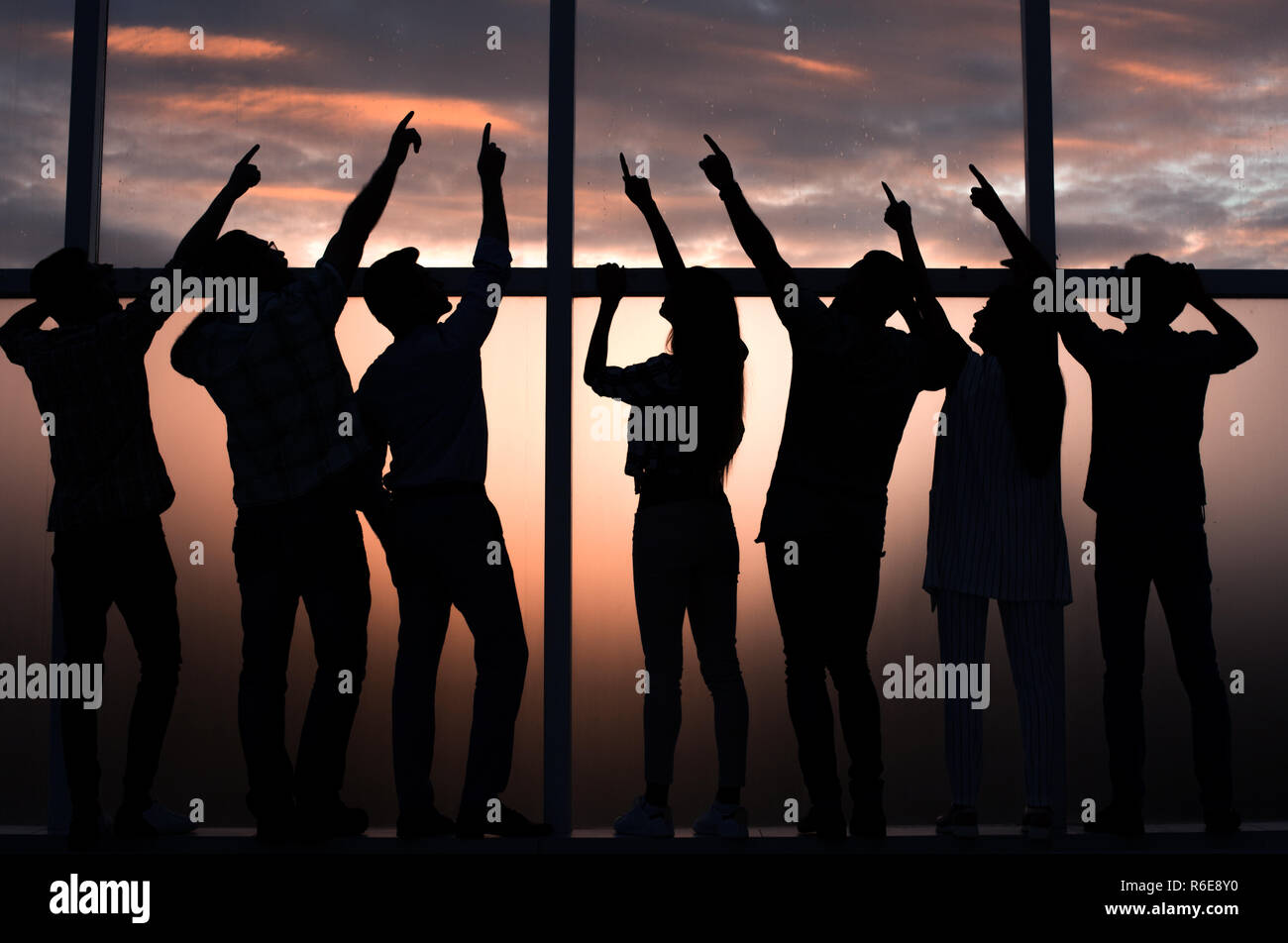 business team pointing through a large office window to blank space ...