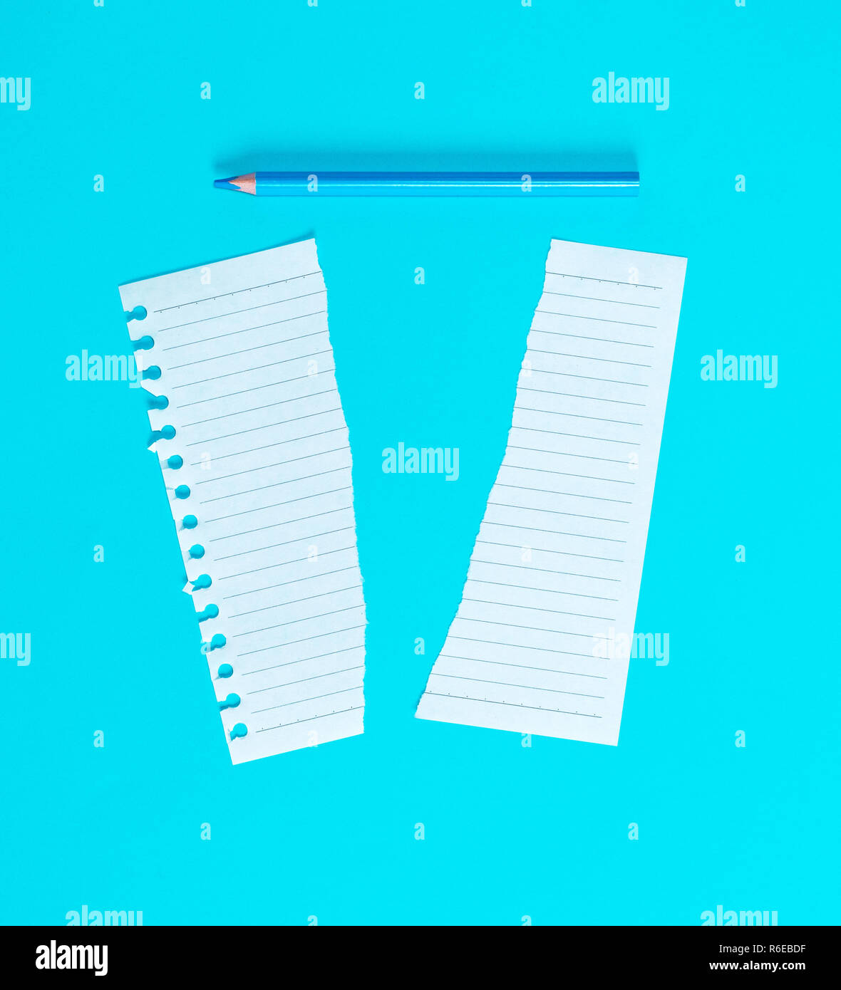 torn in half white blank sheet and wooden pencul on blue background ...