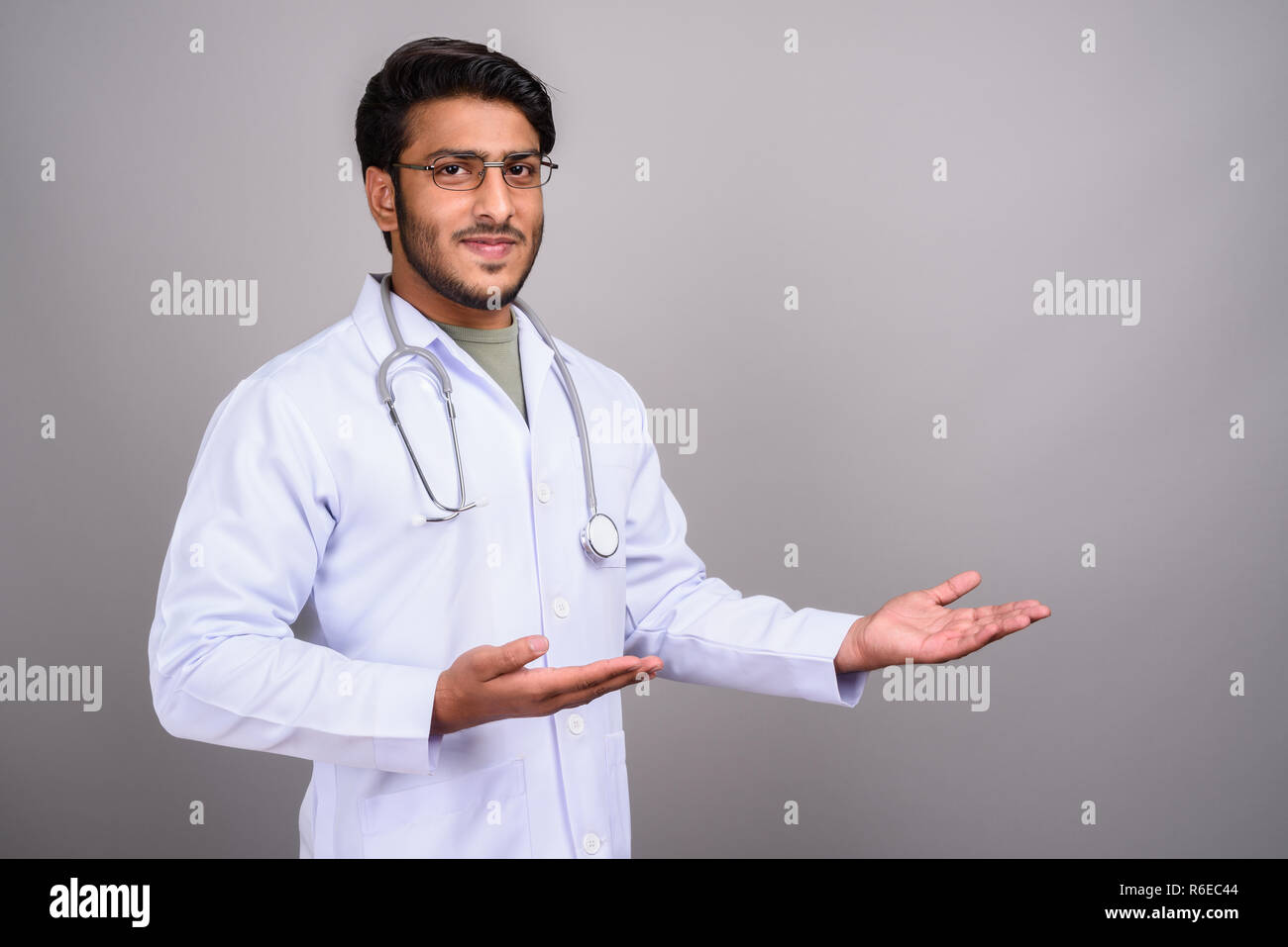 Portrait of Indian man doctor against gray background Stock Photo - Alamy