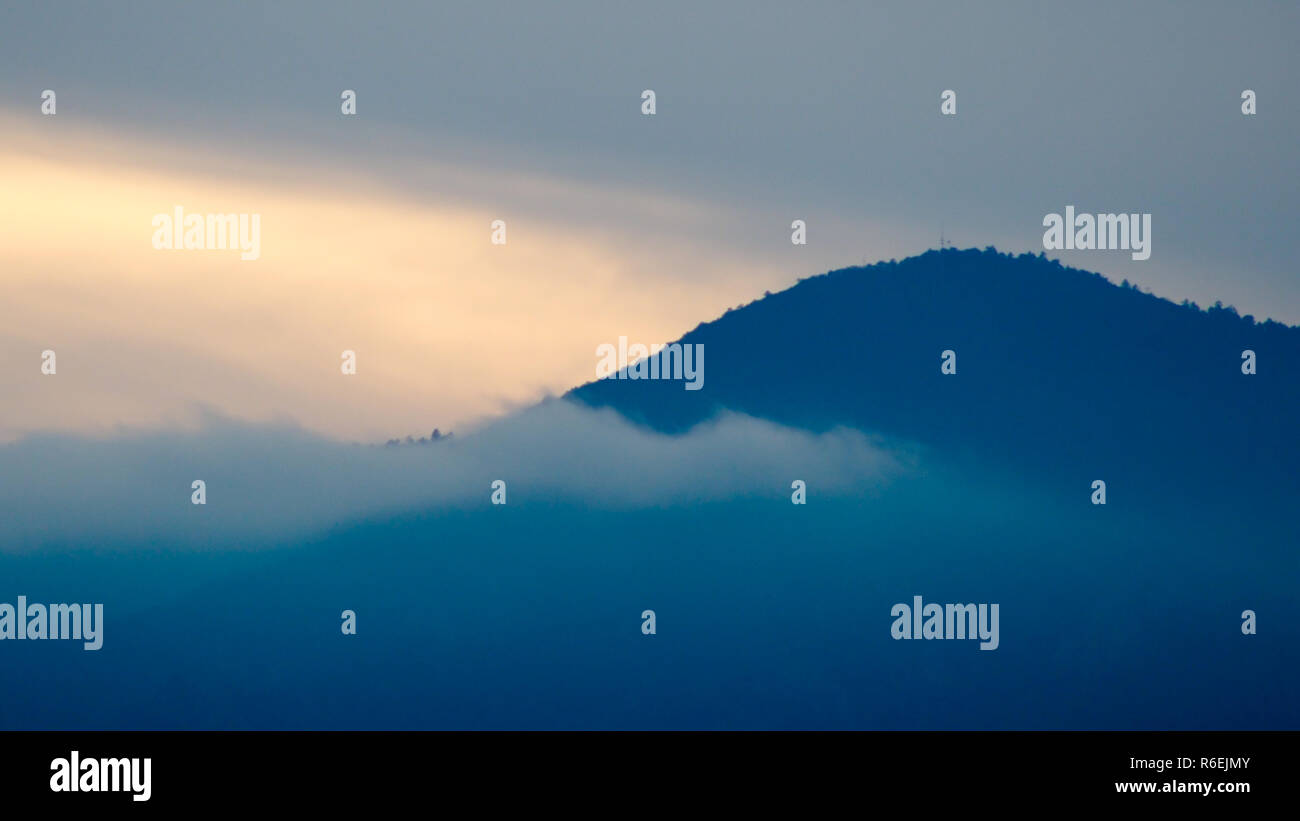 Beautiful blue mountains against a sunset sky with low white clouds ...
