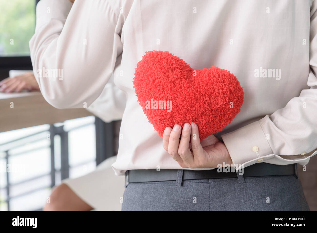 Man holding red heart behind his back to surprise woman Stock Photo - Alamy