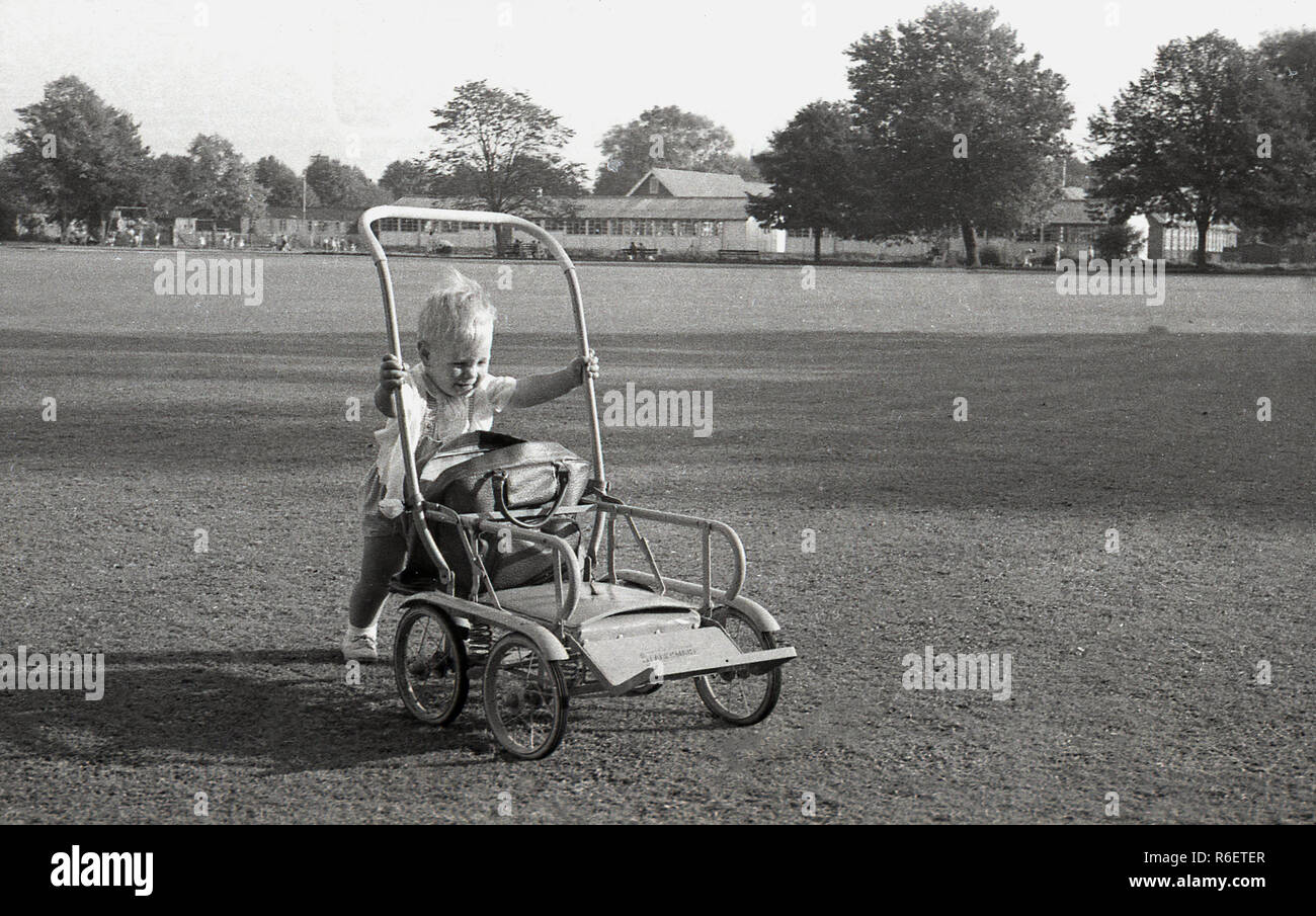 1950s, historical, an infant child pushing a pushchair outside on a ...