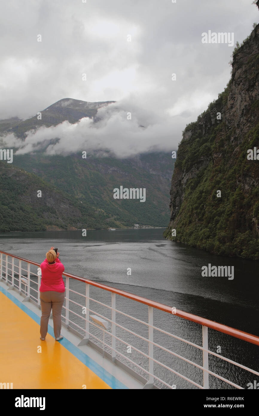 Woman photographs fjord from deck of cruise liner. Geirangerfjord ...