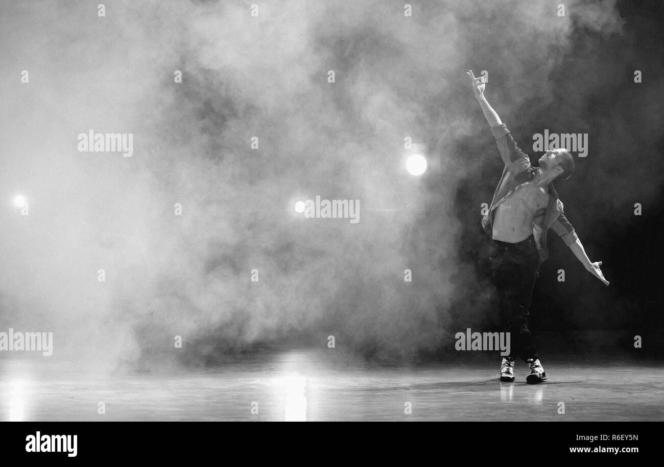 Young and muscular man performing a contemporary dance pose on a stage ...