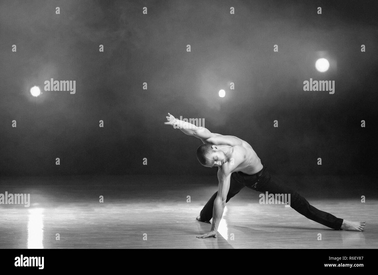 Young and muscular man performing a contemporary dance pose on a stage ...