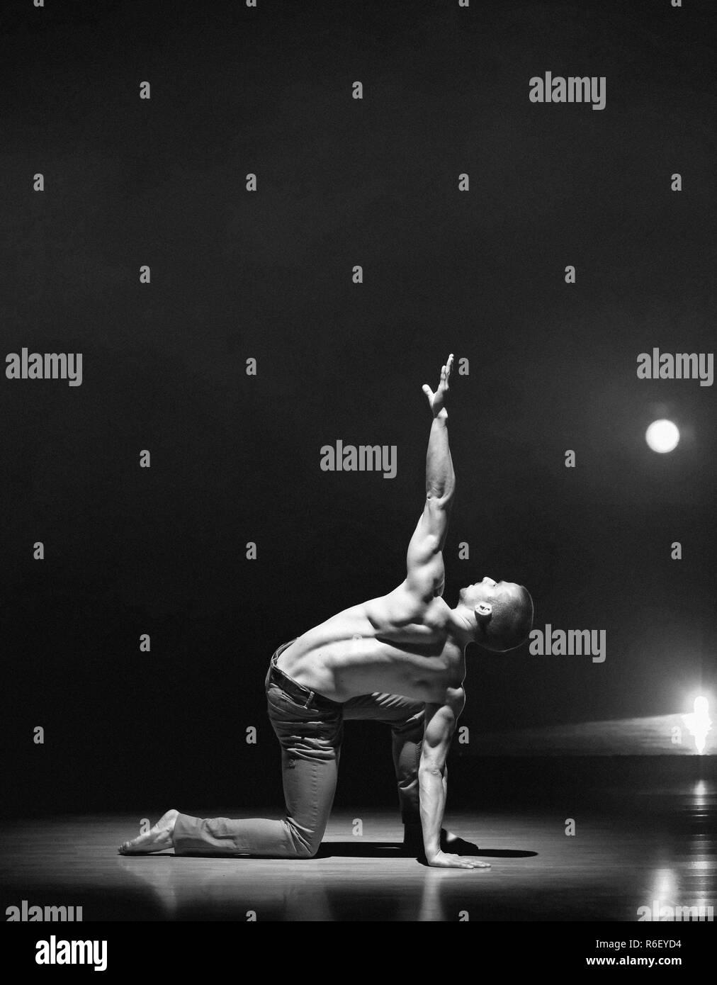 Young and muscular man performing a contemporary dance pose on a stage ...