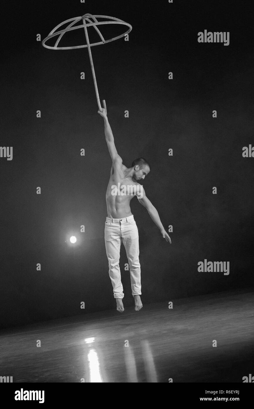 Young and muscular man performing a contemporary dance pose on a stage ...