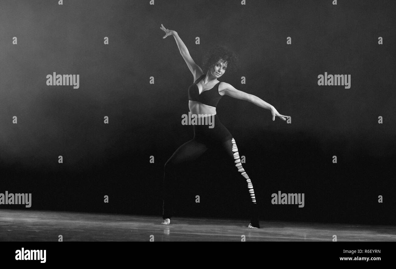 Young and fit woman performing a contemporary dance pose on a stage ...