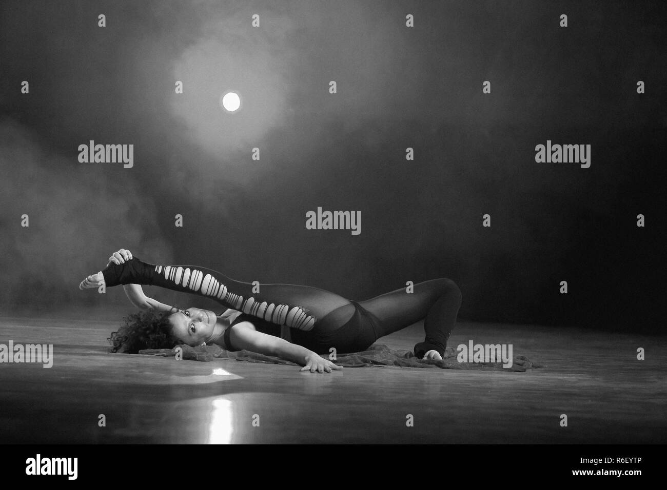 Young and fit woman performing a contemporary dance pose on a stage ...