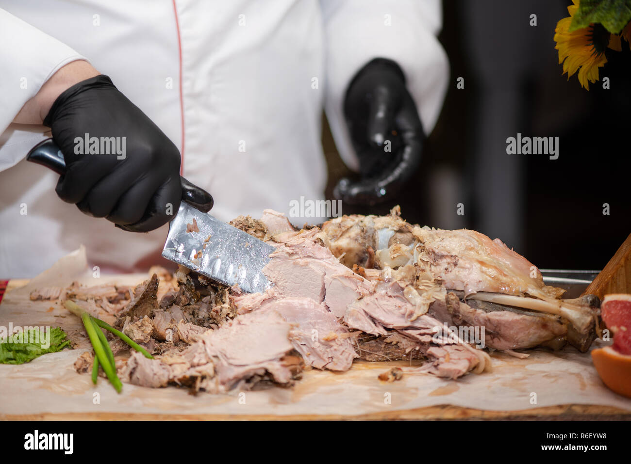 Chief cook cuts into pieces freshly cooked pork thigh, process close up ...
