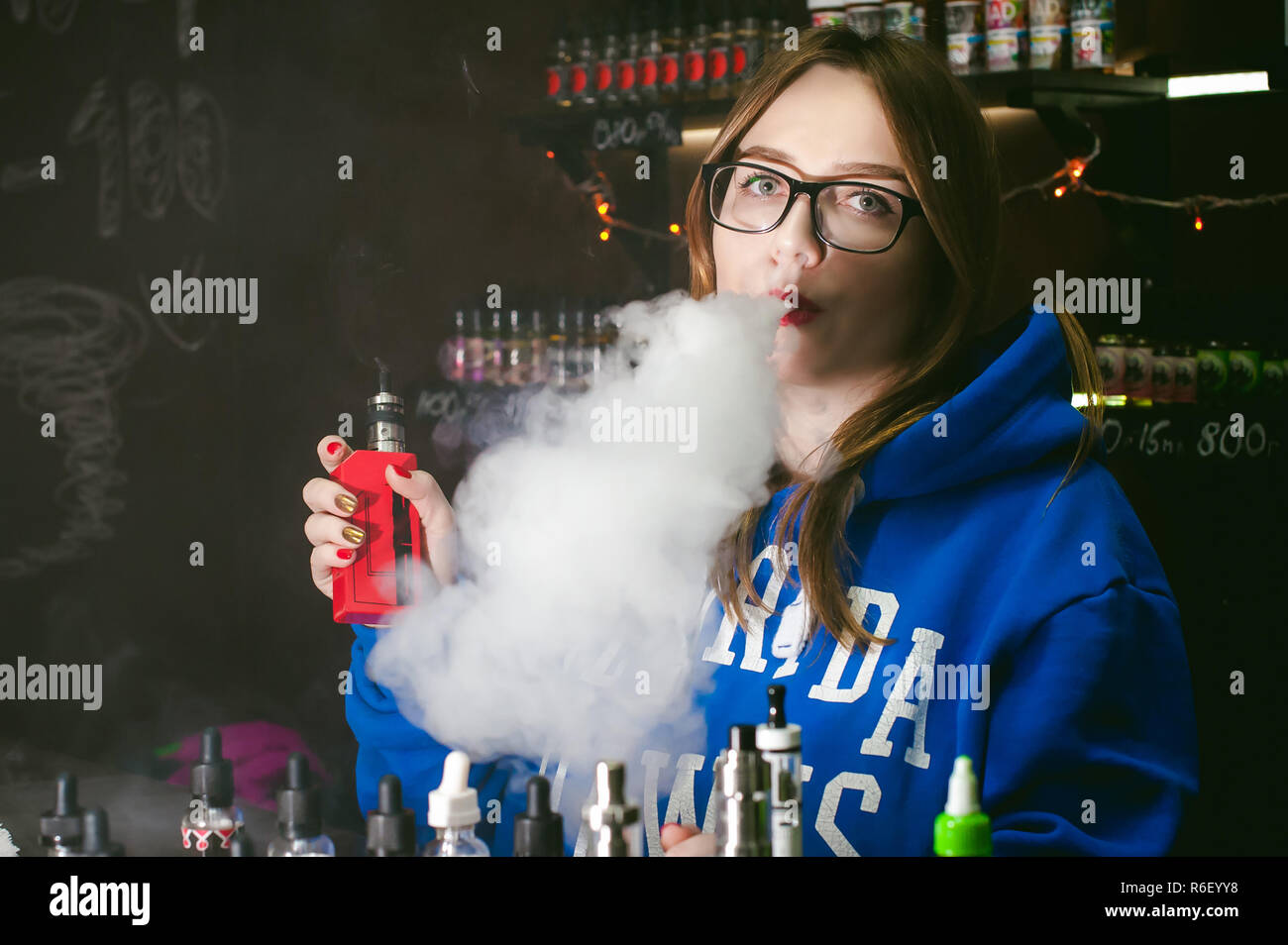 young Cute woman, the seller in vape shop shop, smoking electronic ...