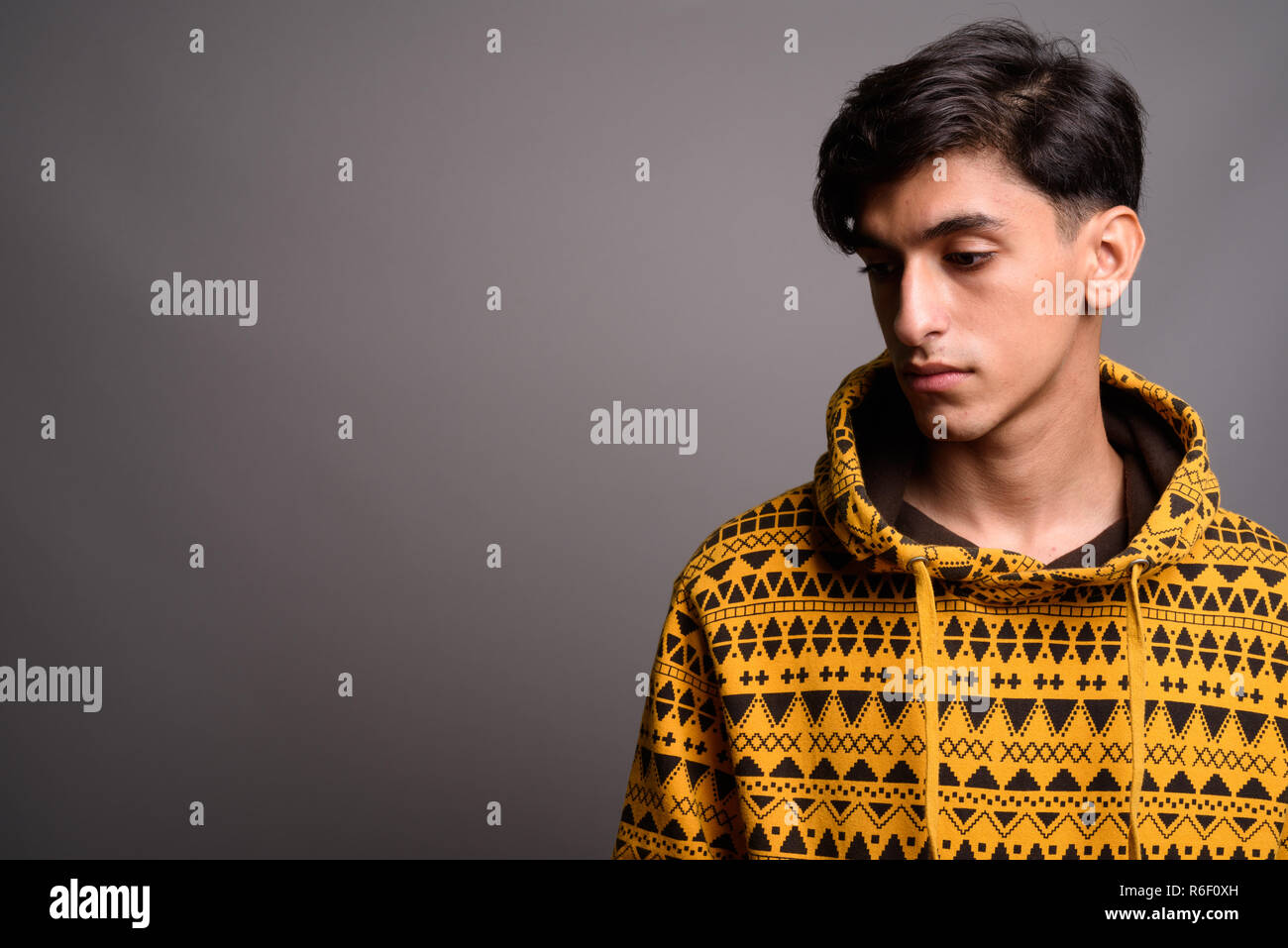 Sad young Persian teenage boy thinking against gray background Stock ...