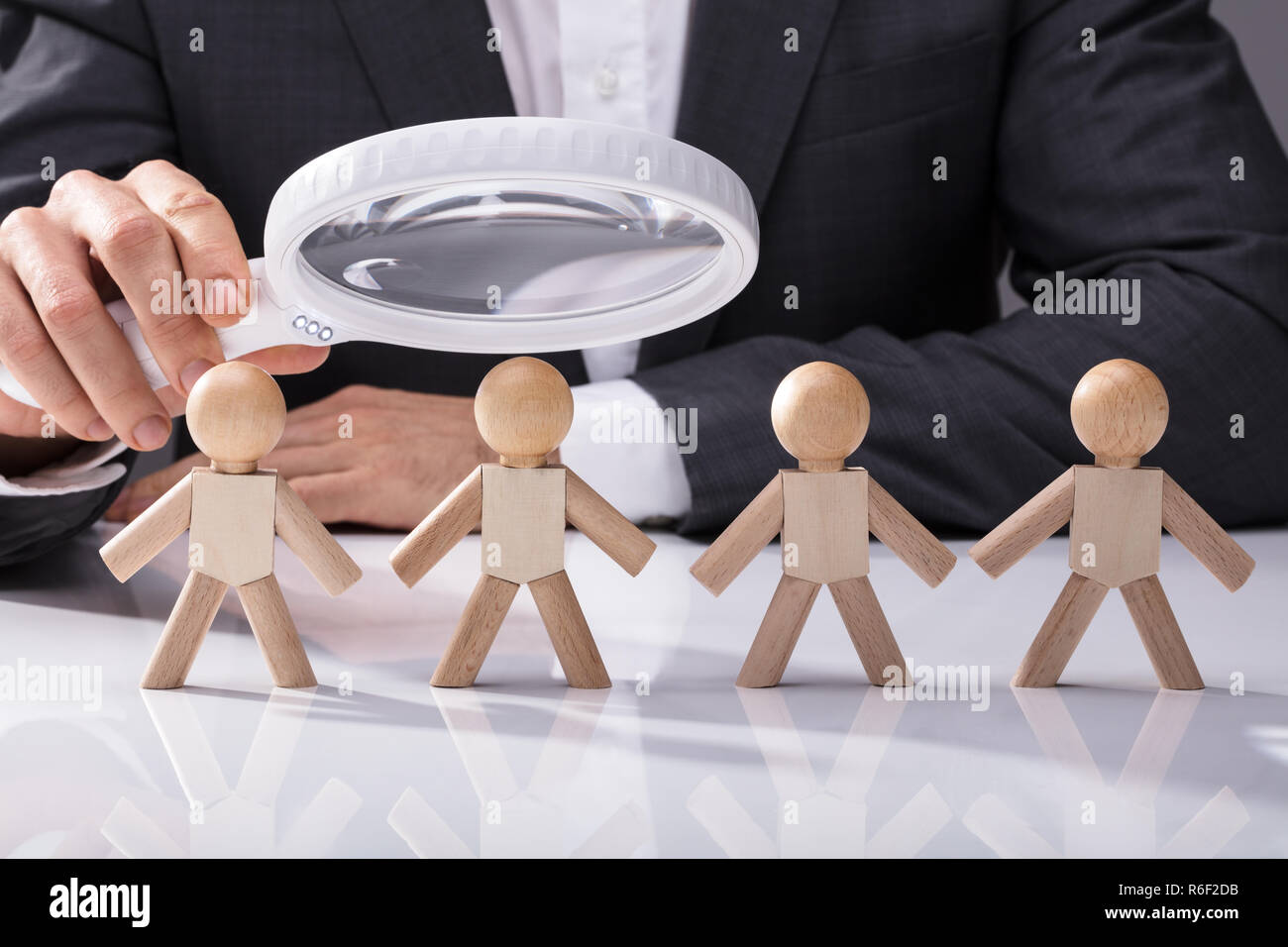 Human Hand Holding Magnifying Glass Over Wooden Figures Stock Photo - Alamy
