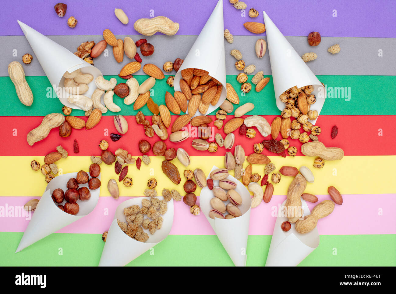 Assorted nuts served in paper cones scattered on a colorful paper ...