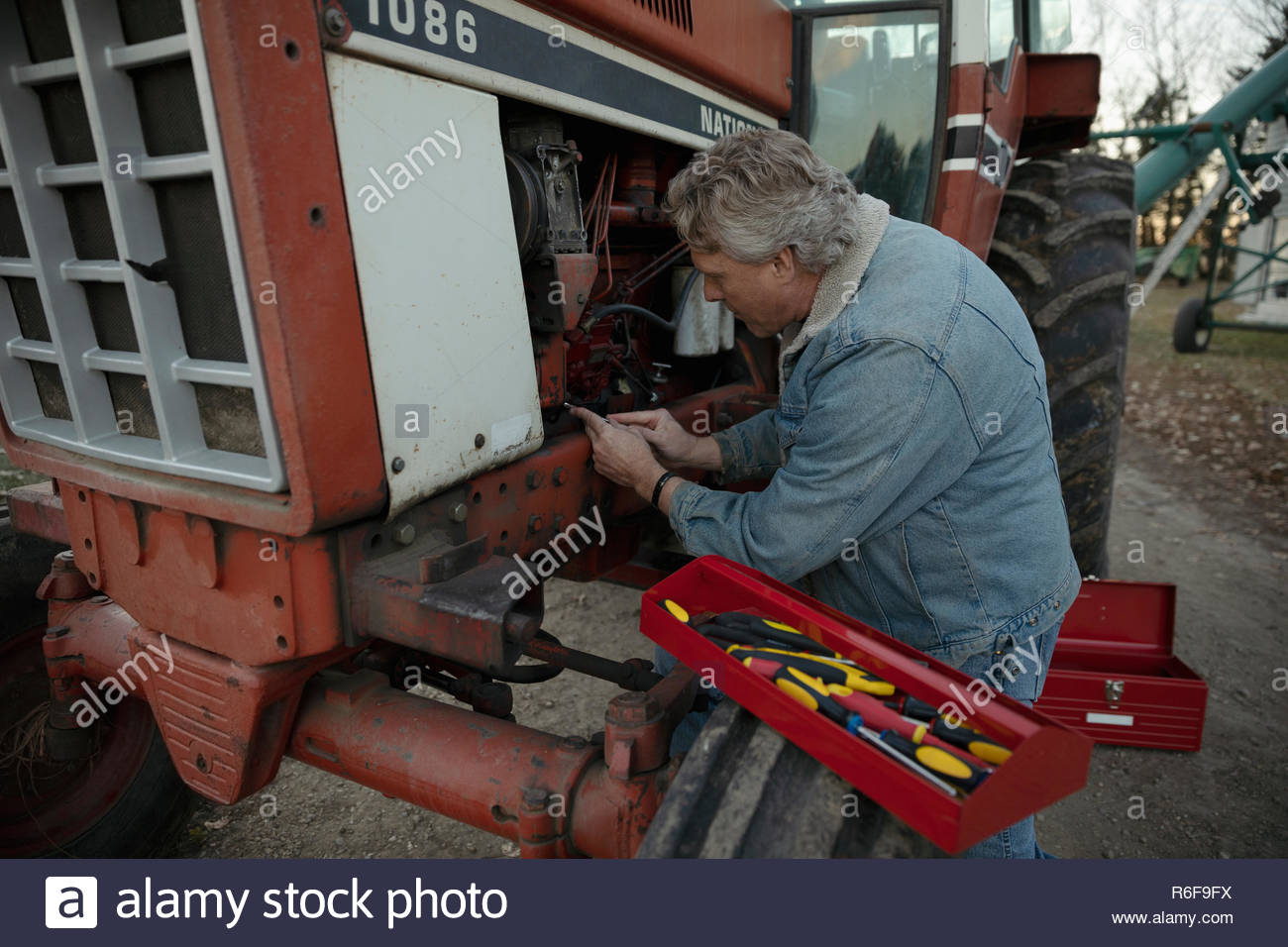 Male farmer with tools fixing tractor Stock Photo - Alamy