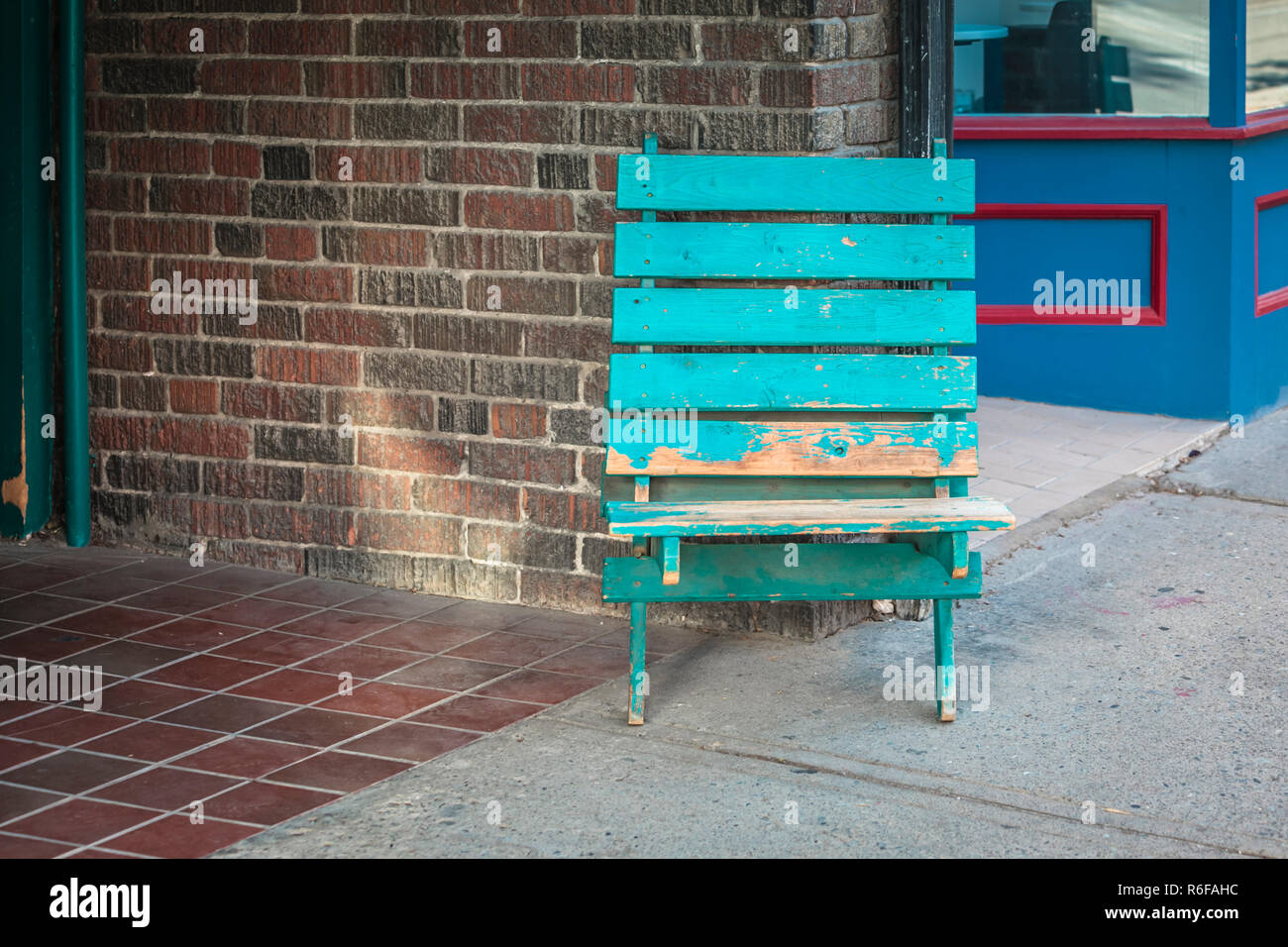 Unoccupied old blue bench in front of a brick wall store Stock Photo ...