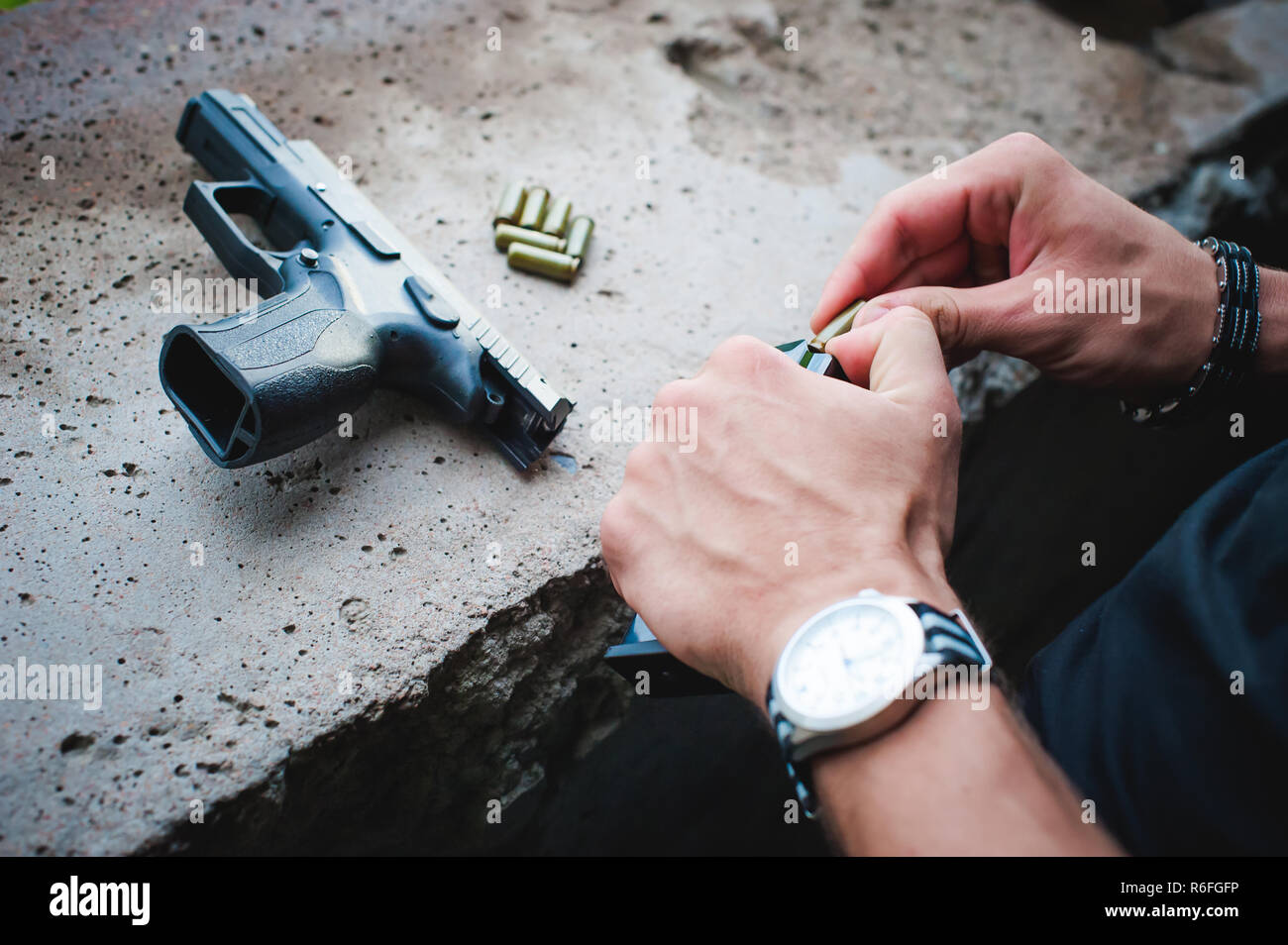 Man charges clip of pistol with bullets. Photo hands of paramilitary ...