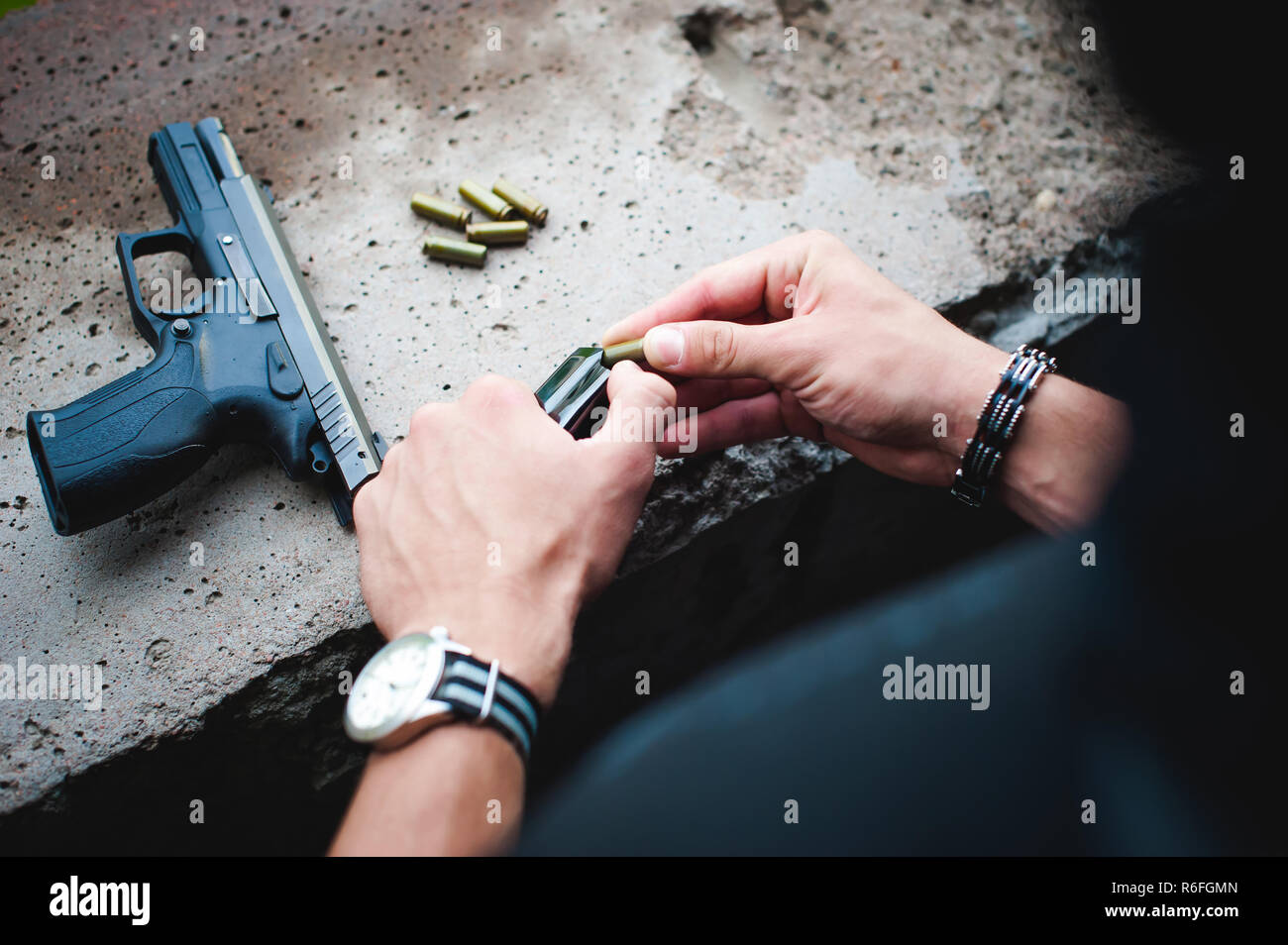 Man charges clip of pistol with bullets. Photo hands of paramilitary ...