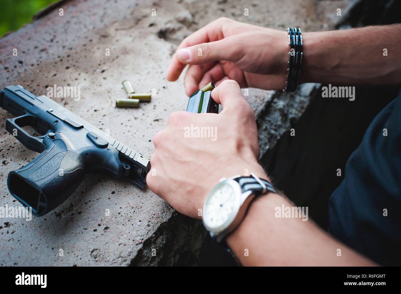 Man charges clip of pistol with bullets. Photo hands of paramilitary ...