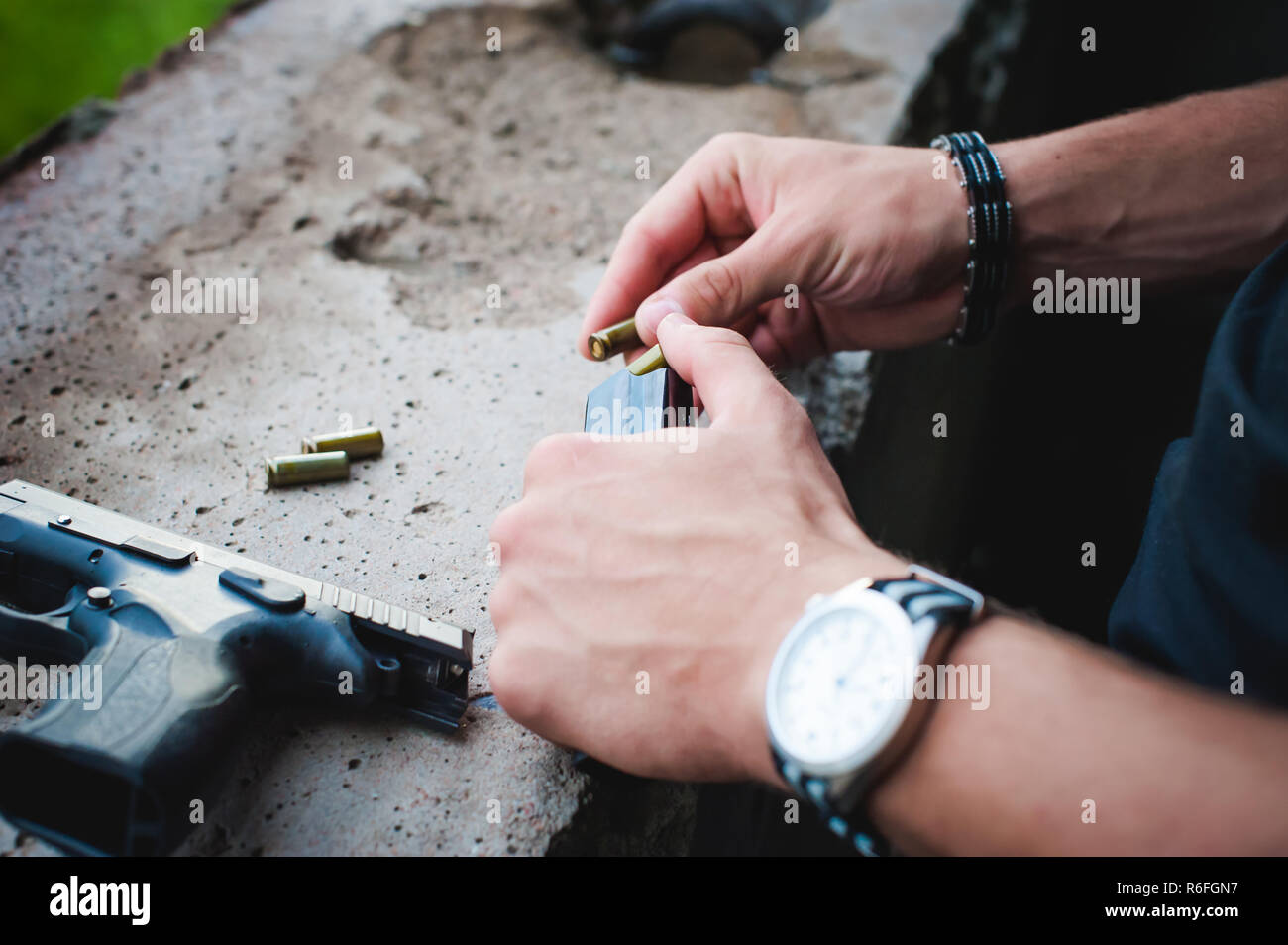 Man charges clip of pistol with bullets. Photo hands of paramilitary ...