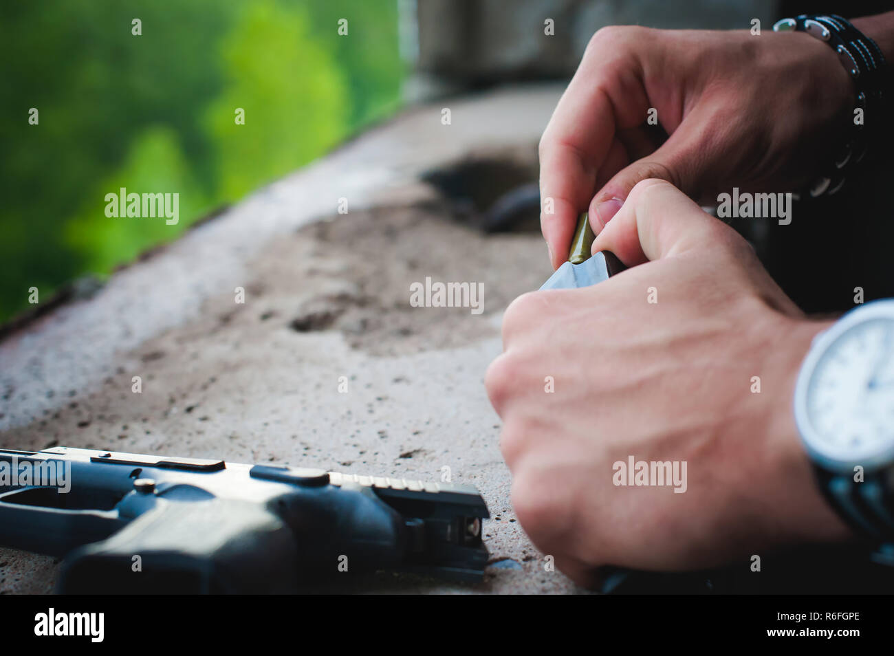 Man charges clip of pistol with bullets. Photo hands of paramilitary ...