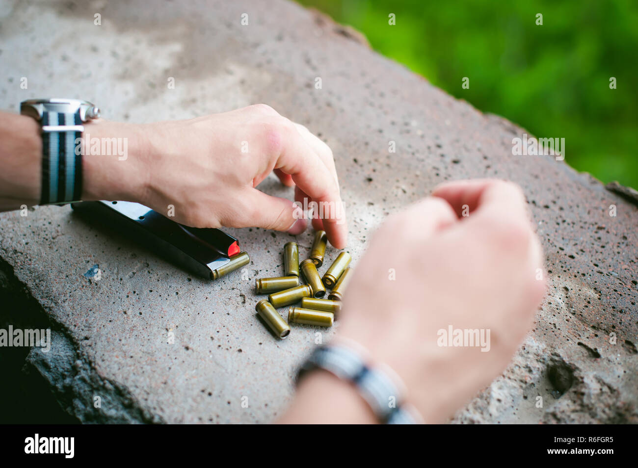 Man charges clip of pistol with bullets. Photo hands of paramilitary ...