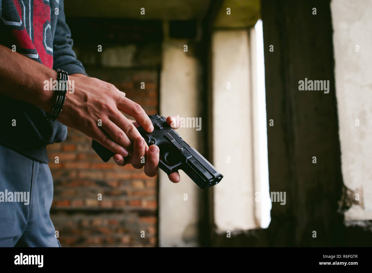 Dangerous athletic man holding a gun in his hand, close-up Stock Photo ...