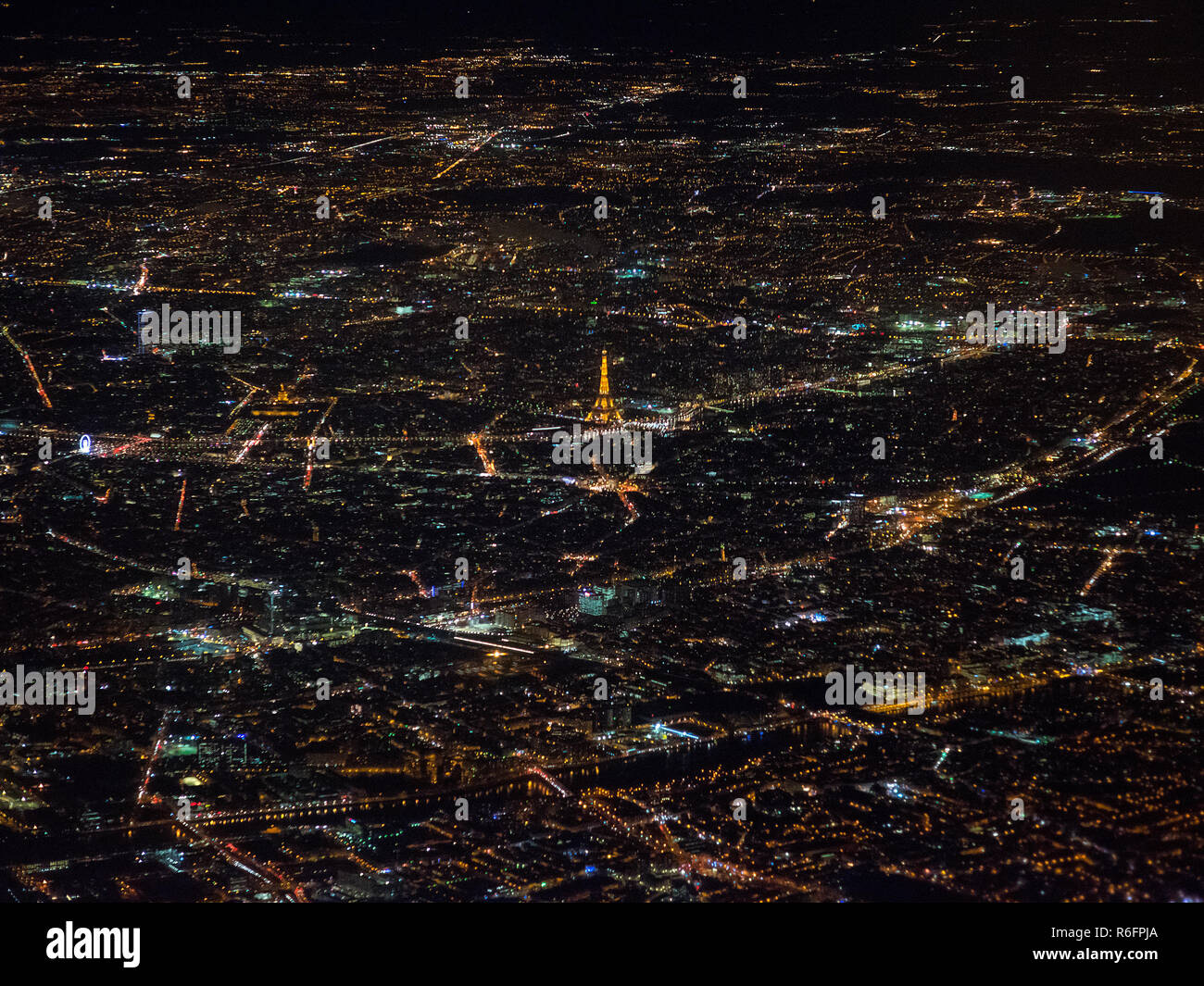 Taken from a plane, a cityscape of Paris by night with the Eiffel Tower ...
