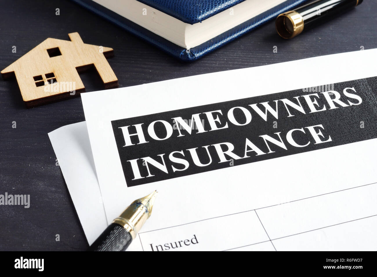 Homeowners insurance policy and model of home Stock Photo - Alamy