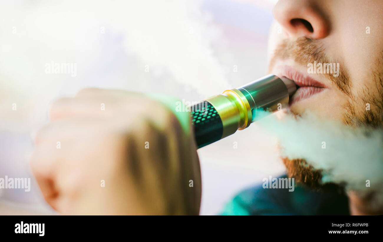 young vaper man with beard vaping mechanical mod. Guy smokes an ...