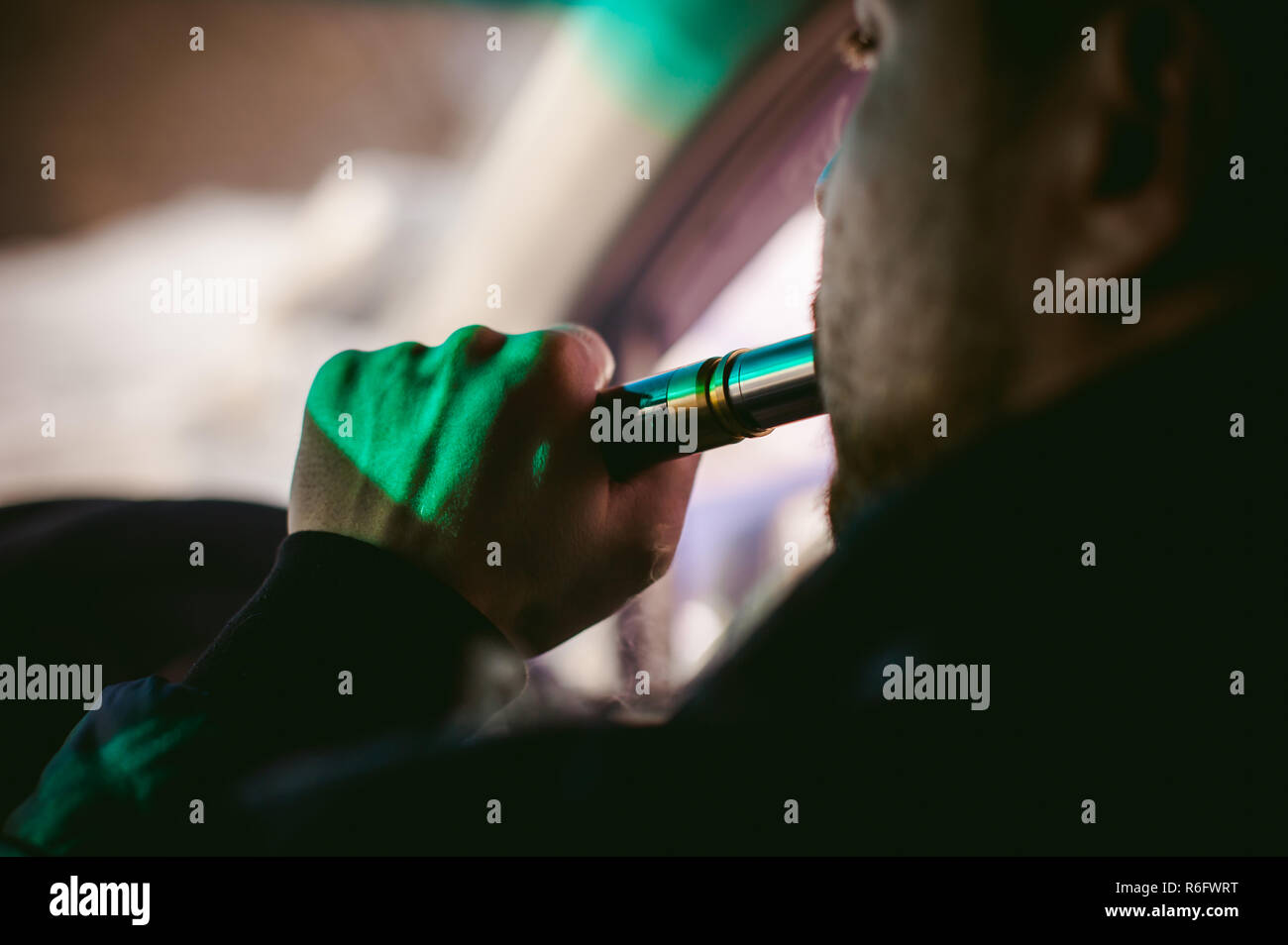 young vaper man with beard vaping mechanical mod. Guy smokes an ...