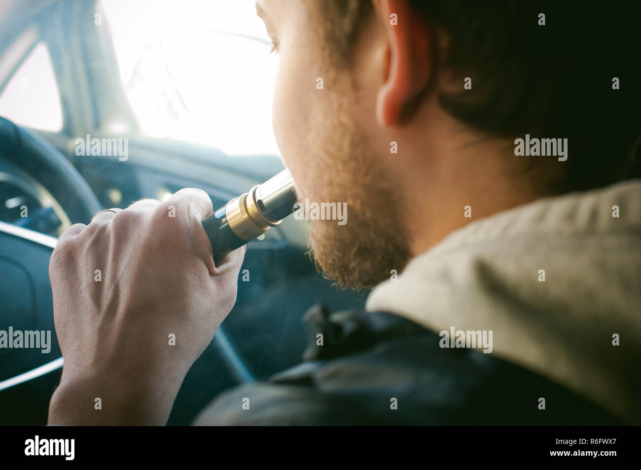 young vaper man with beard vaping mechanical mod. Guy smokes an ...