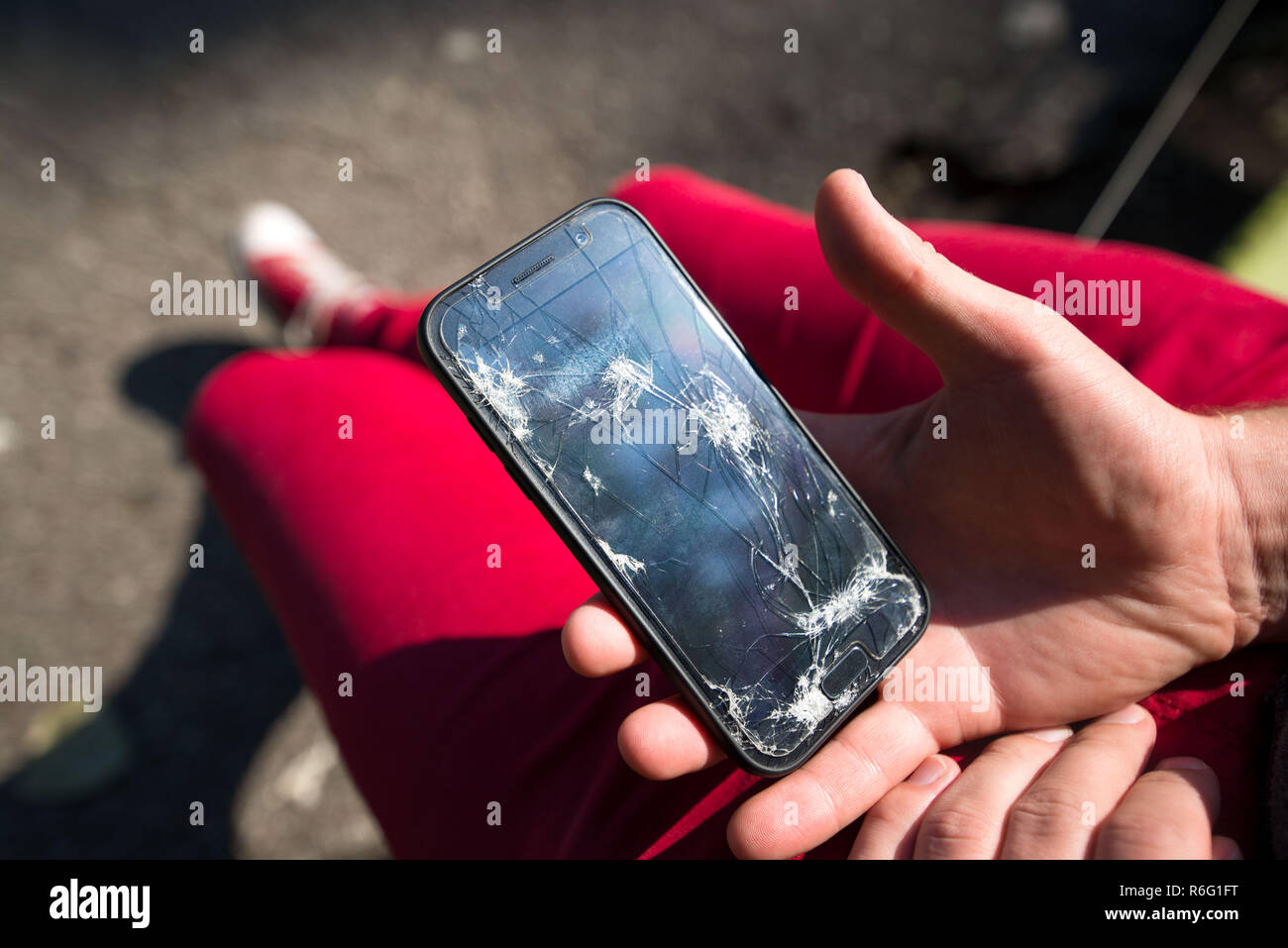 Broken and damaged smartphone with cracks on glass, screen. Young man ...