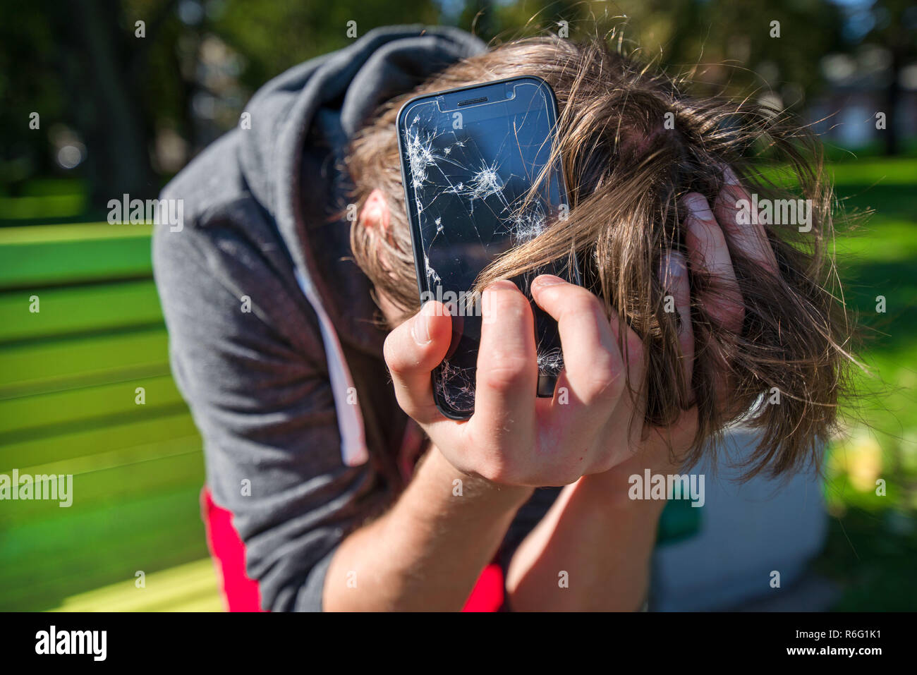 Broken and damaged smartphone with cracks on glass, screen. Young man ...