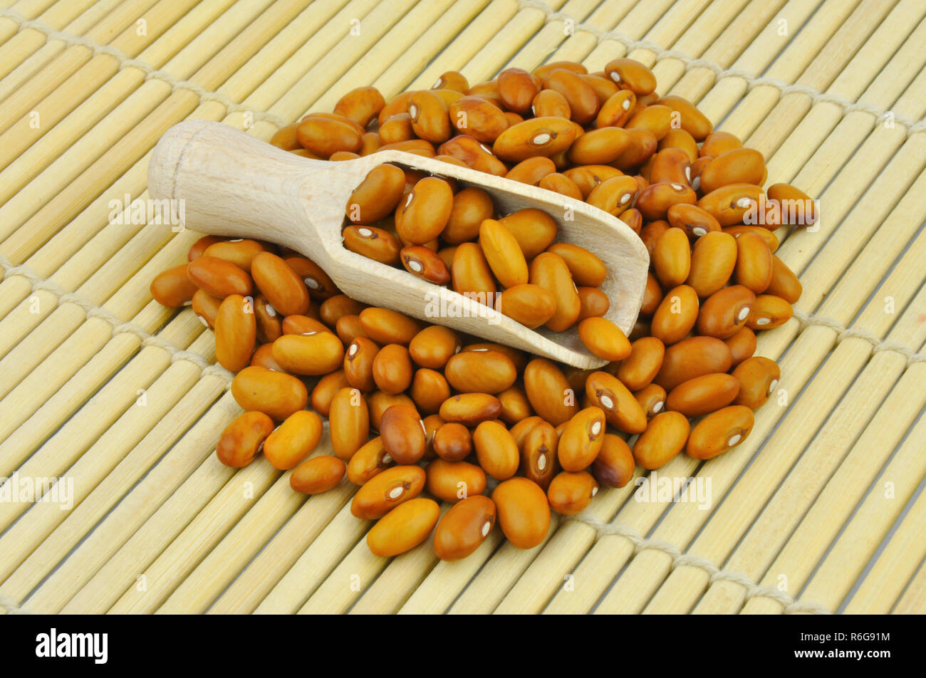 Orange beans on bamboo mat with wooden scoop Stock Photo - Alamy