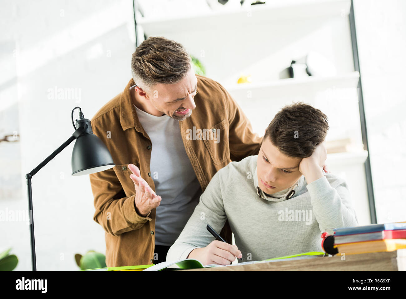 angry father yelling at teen son, boy covering ears Stock Photo - Alamy